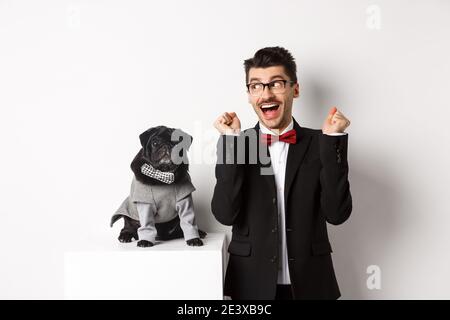 Cheerful dog owner in suit celebrating Christmas with dog, taking ...