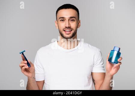 Handsome hispanic man holding razor looking positive and happy standing ...