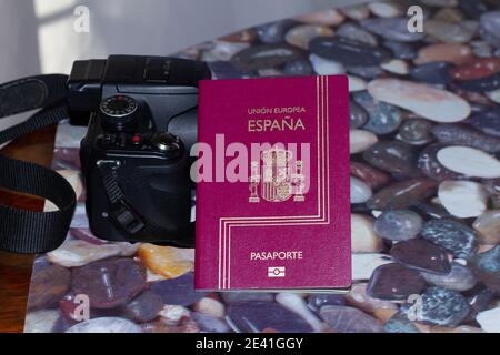 Pink Spanish passport and a digital camera on a table - travel concept ...