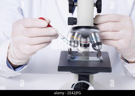 Closeup of a scientist examining toxic substances under a microscope in ...