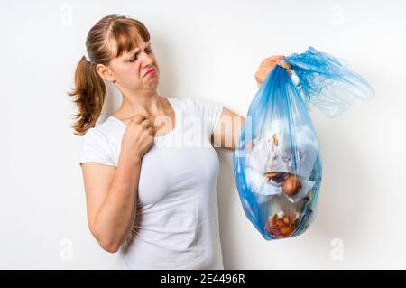 Young female holding a smelly bin bag isolated on white background ...