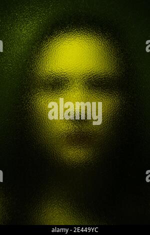 Headshot of anonymous person standing in room with dim green light and ...