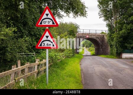 Low bridge warning signs and height restriction markings over a narrow ...