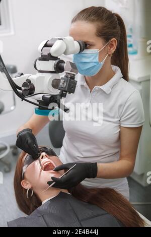 Dentist using dental microscope treating patient with braces in dental ...