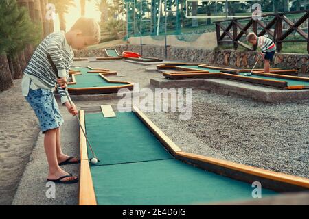 Kids playing mini golf on summer evening on the territory of the hotel ...