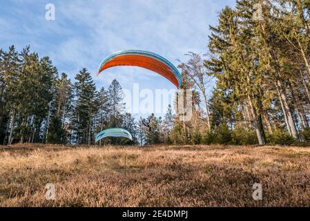 Taking off hobby paraglider pilot on a mountain slope with professional ...