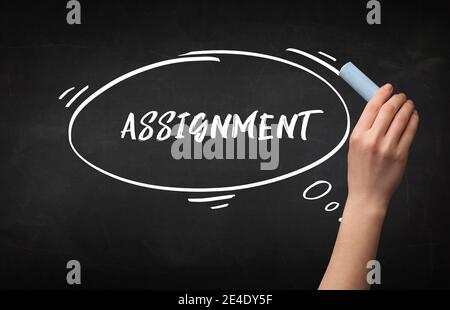 Hand drawing ASSIGNMENT inscription with white chalk on blackboard ...