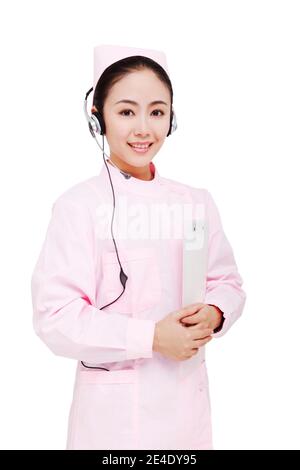 Smiling nurse wearing headset and scrubs, typing on computer in home ...