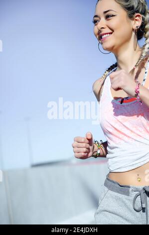 Smiling young sportswoman running on track Stock Photo - Alamy