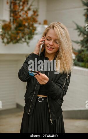 Young woman with credit card and mobile phone shopping online in ...