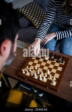 Man and woman playing chess game sitting on table at home Stock Photo ...