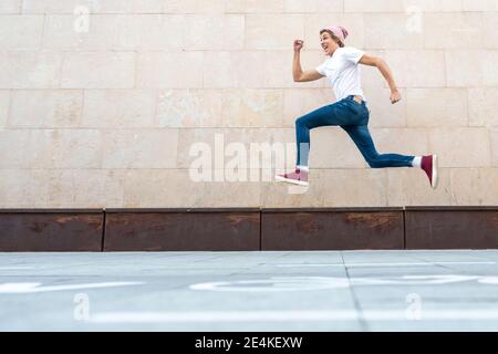Carefree young man running against wall Stock Photo - Alamy