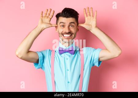 Silly and childish guy in suspenders and bow-tie, mocking someone ...