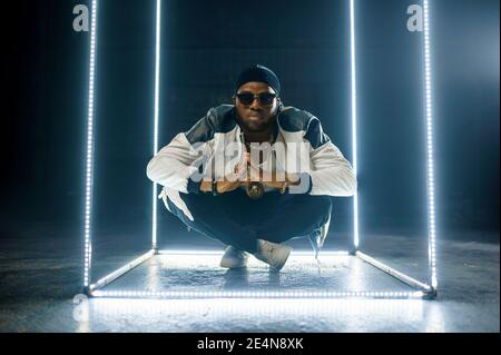 Stylish rapper in gold jewelry and sunglasses, dark background. Hip-hop ...