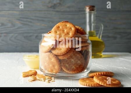 Jar with tasty crackers, cheese, oil and olives on color background ...