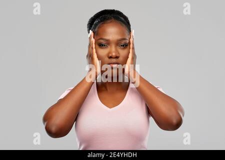 African american woman suffering for ear pain sitting on sofa at home ...