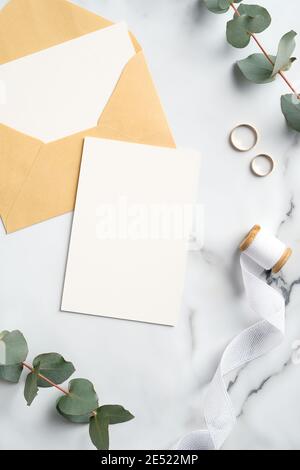 Blank cards on marble table near black feathers and golden leaves close ...