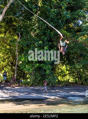 Tarzan exercise with jumping into shallow water on the beach in ...