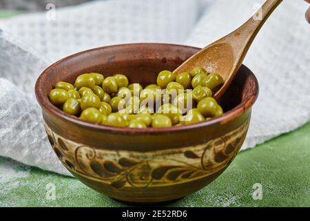 A bowl of boiled green peas with a wooden spoon and a tablecloth on a ...