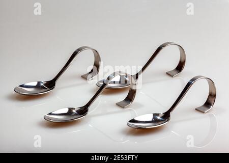 A silver spoon with curved handle photographed half sideways isolated ...