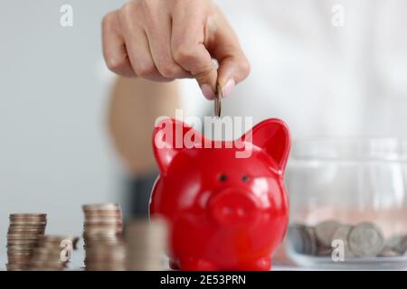 Female hand throwing cash coins into red piggy bank closeup Stock Photo ...