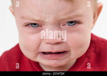 A child with tears his eyes is crying loudly with his mouth wide open ...