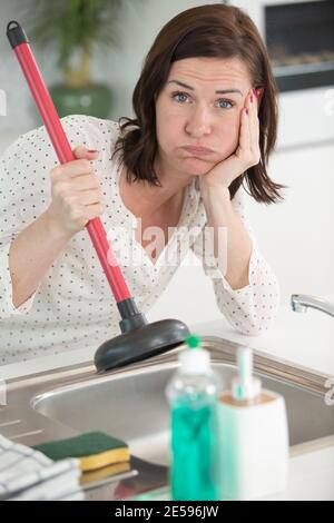 Unhappy Woman Using Plunger In Clogged Sink Stock Photo - Alamy