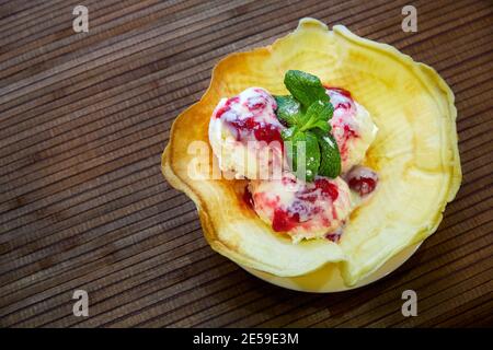 Ice cream balls drizzled with jam on a waffle plate. Close-up ...