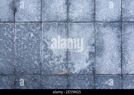 Salt spread on icy pavement in the city. Bricks covered with salt ...