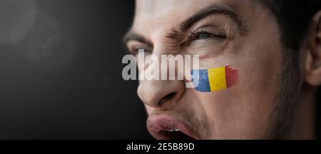 A screaming man with the image of the Romania national flag on his face ...