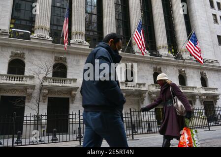 Pedestrians wearing protective masks pass a parked USPS delivery truck ...