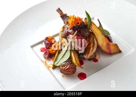 Duck leg with pear on a white plate Stock Photo - Alamy