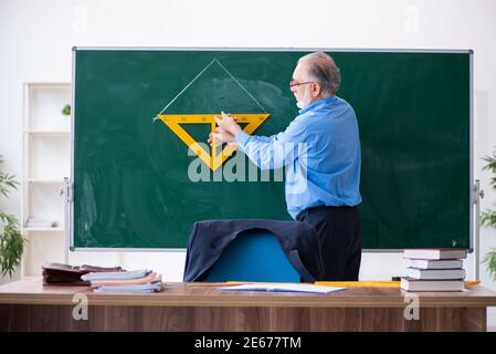 Senior male geometry teacher holding triangle Stock Photo - Alamy