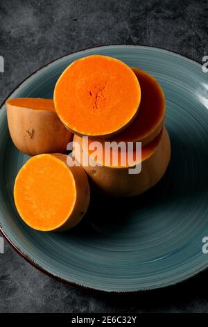 Vertical top view of sliced butternut squash on a plate isolated dark ...