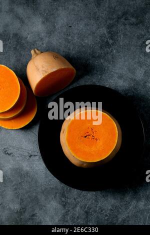 Vertical top view of sliced butternut squash on a plate isolated dark ...