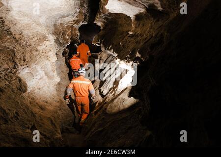 Three men, strong physique, explore the cave. Men dressed in special ...