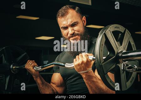 Healthy Powerlifter Man Working Out Legs With Barbell In A Gym - Squat ...