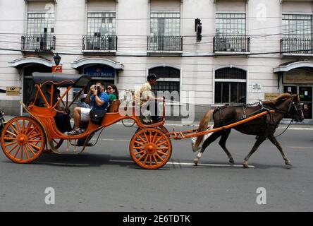 A horse drawn carriage known as a Kalesa being driven in downtown Cebu ...