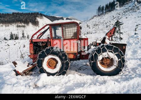 Rural mountain scene of an old tractor parked in a snowy courtyard on a ...