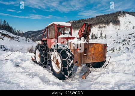 Rural mountain scene of an old tractor parked in a snowy courtyard on a ...