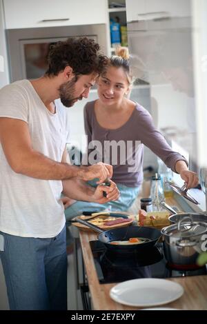 A young guy enjoying preparing a meal for his girlfriend in a home ...