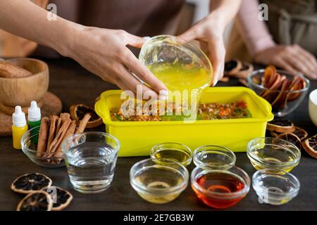Hands of female pouring melted soap mass into silicone container with ...