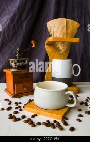 A vertical shot of a wooden coffee drip set with mugs on a table ...