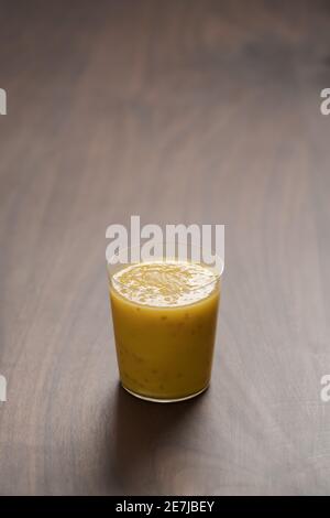 Mango lulo smoothie on walnut wood table with copy space, shallow focus ...