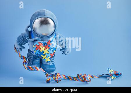 Autism awareness background. Blue plush astronaut toy with puzzle heart ...