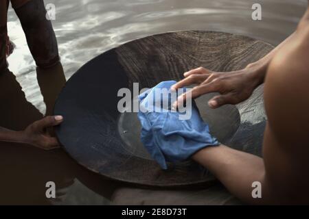 Gold miners processing gold particles with mercury amalgamation on a ...