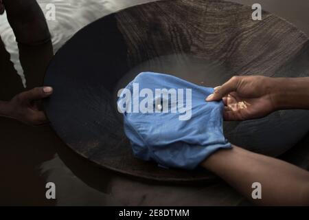 Gold miners processing gold particles with mercury amalgamation on a ...