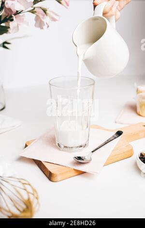 Crop anonymous person pouring fresh beverage into glass bottle from ...