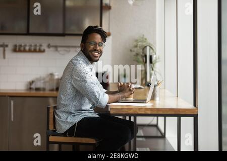 distracted african american freelancer looking away near laptop and cup ...