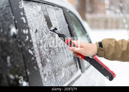A driver removes ice from car after freezing rain (black ice) in Usti ...